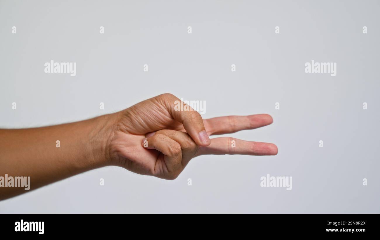 Man's hand making a two-finger peace sign against a neutral background ...