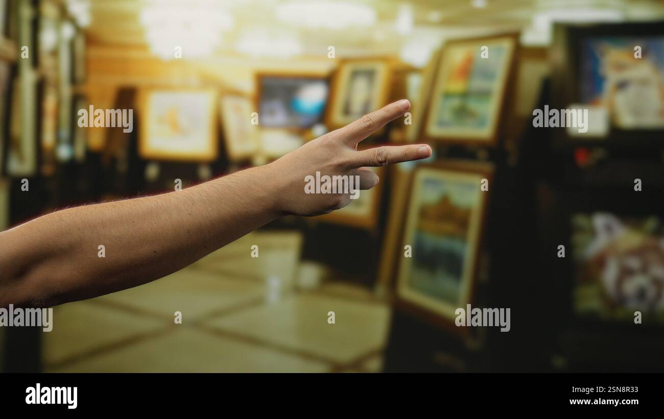Hand gesture inside art gallery displaying paintings with a man's arm ...