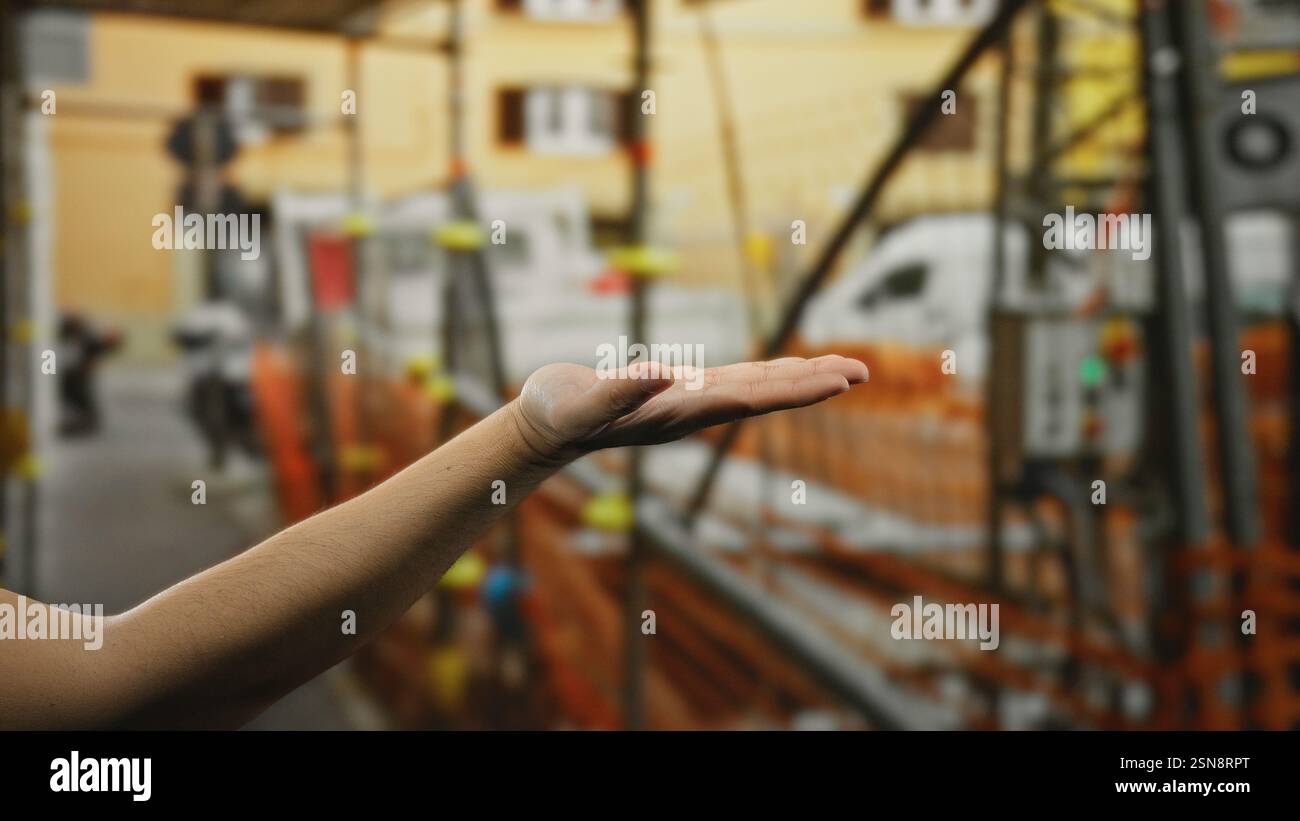 Man holding out hand at outdoor construction site with blurred ...