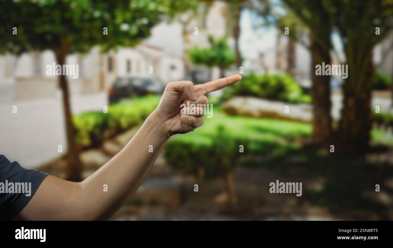 Man pointing hand in an outdoor city street with blurred urban ...
