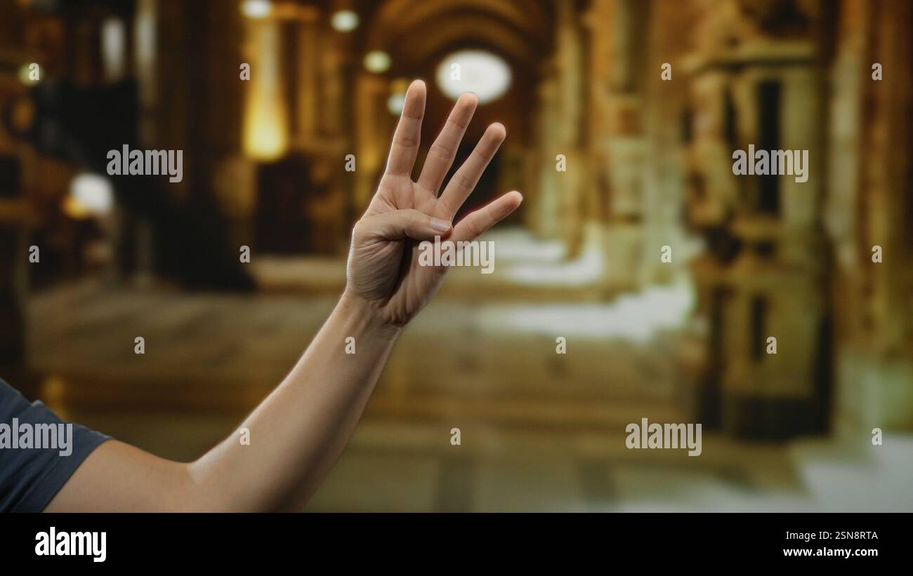 Man's hand showing four fingers in a historic museum room, highlighting ...