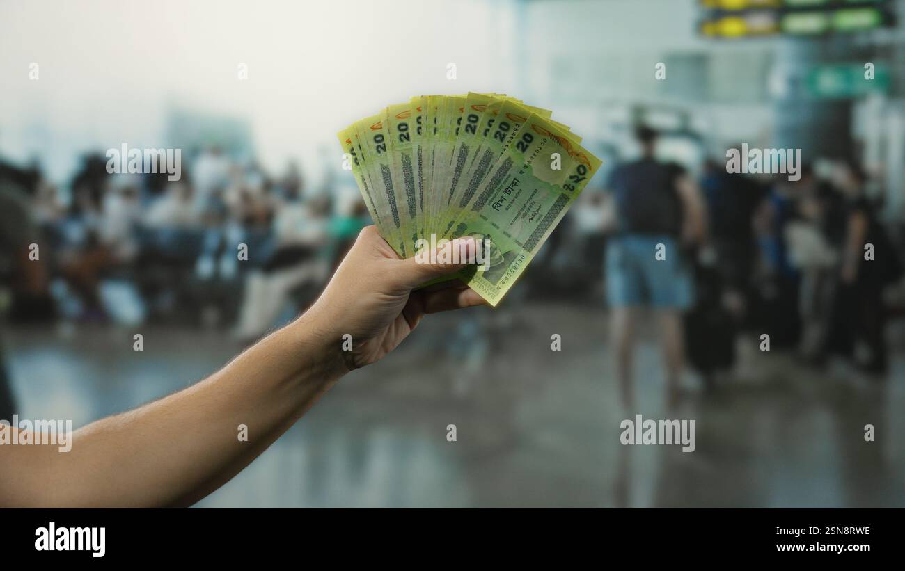 Man holding bangladeshi taka banknotes indoors at an airport ...