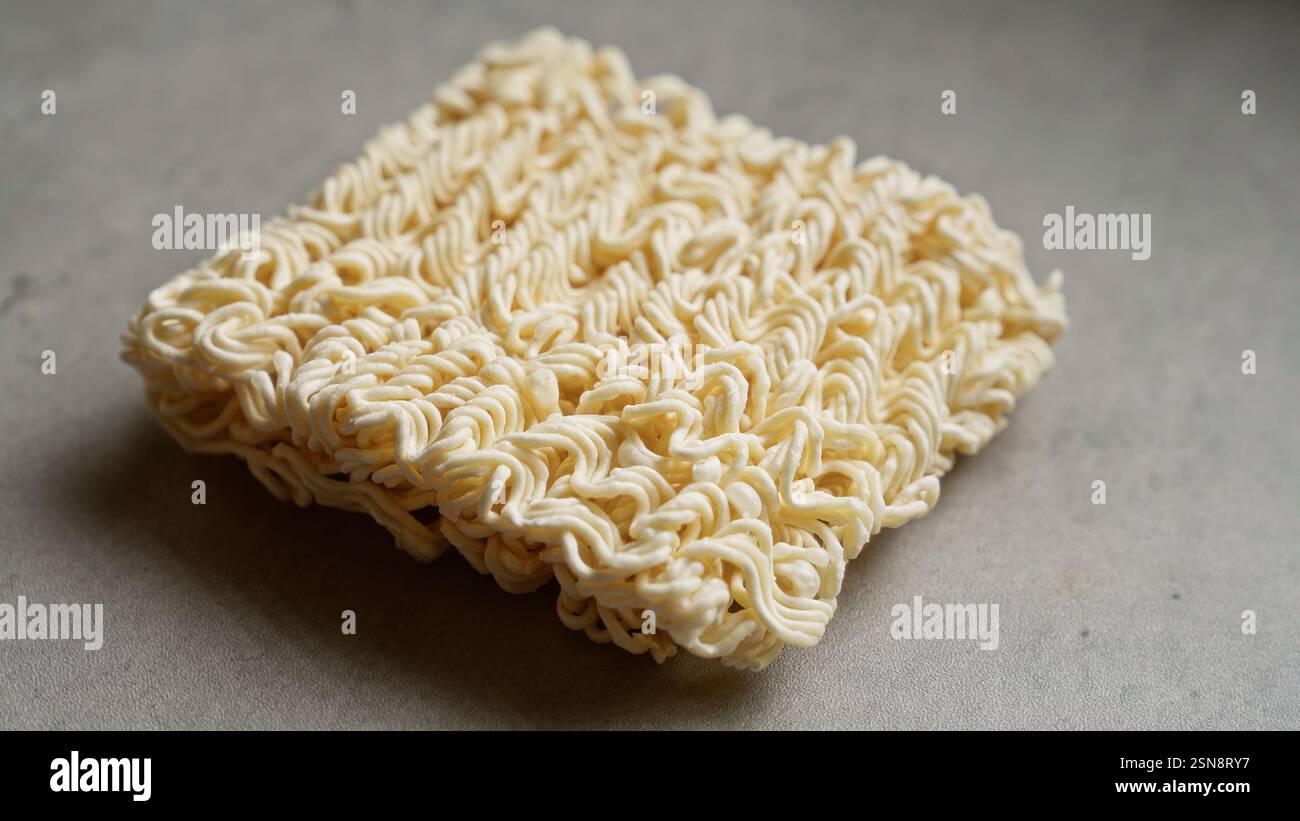 Stock image showcasing a block of uncooked instant noodles on a gray ...