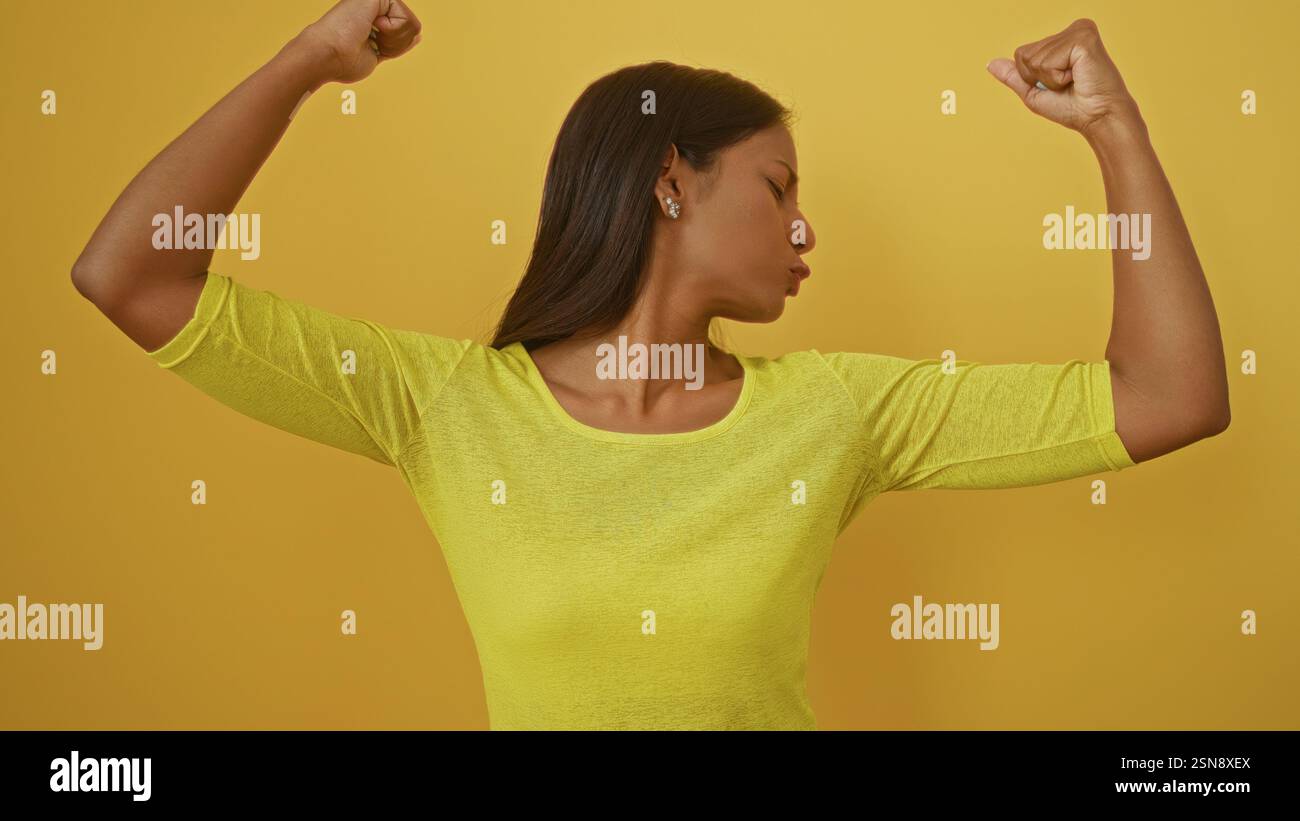 Young latina woman flexing her arms in strength pose over a bright ...