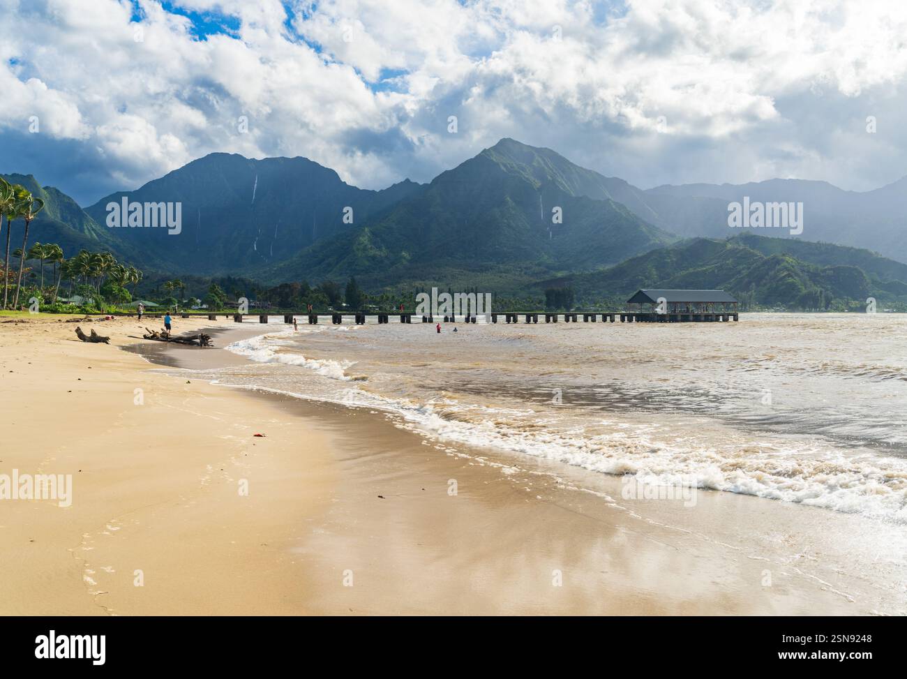 Hanalei Pier and beach are framed by dramatic mountains and sky in this ...
