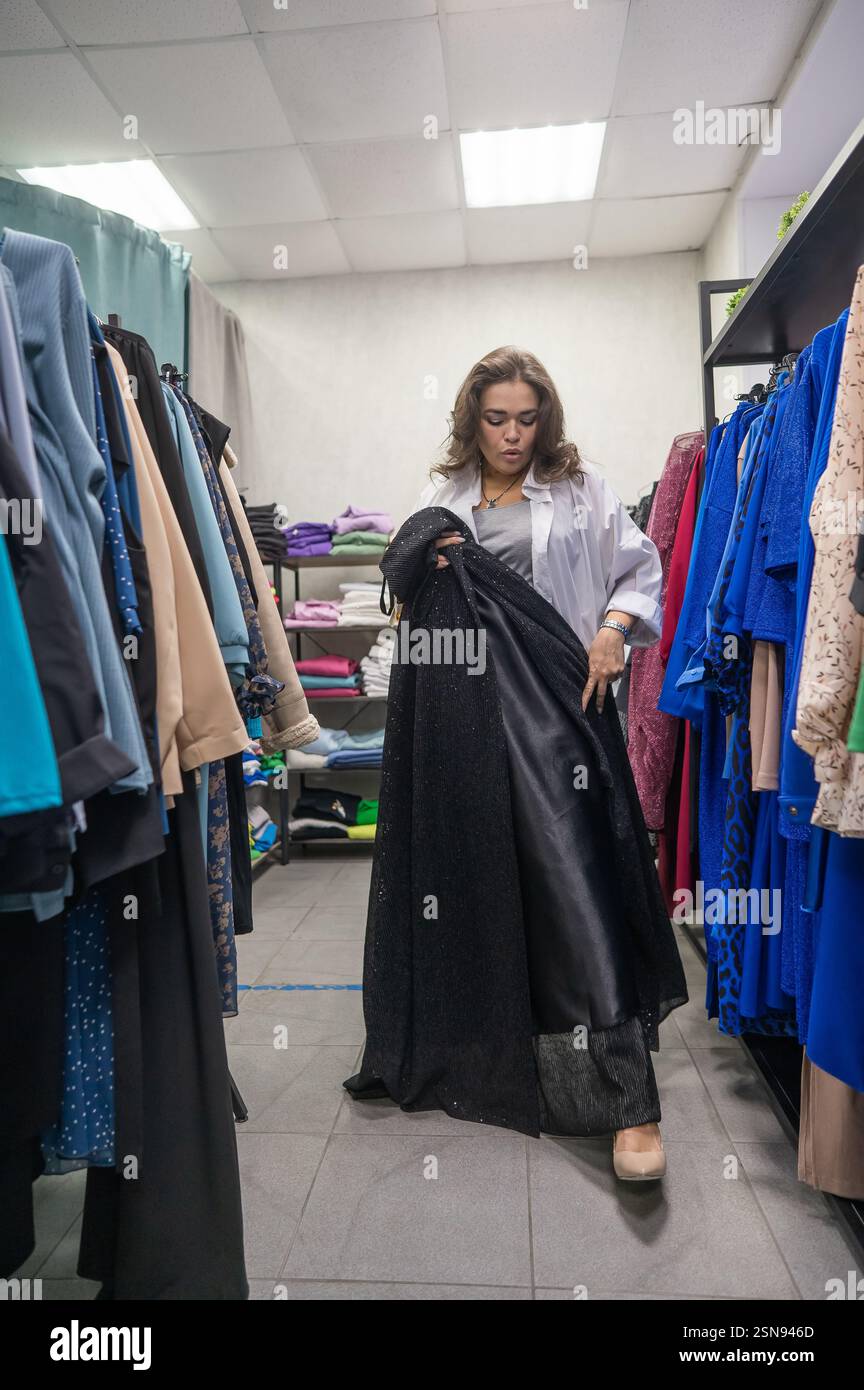 A fat woman chooses clothes in a plus size store. Vertical photo Stock ...