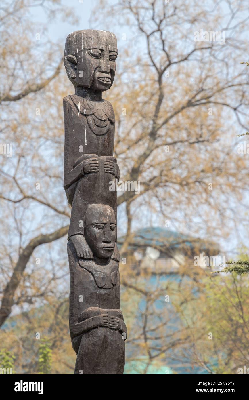 A handcrafted wooden totem pole featuring two carved tribal figures ...