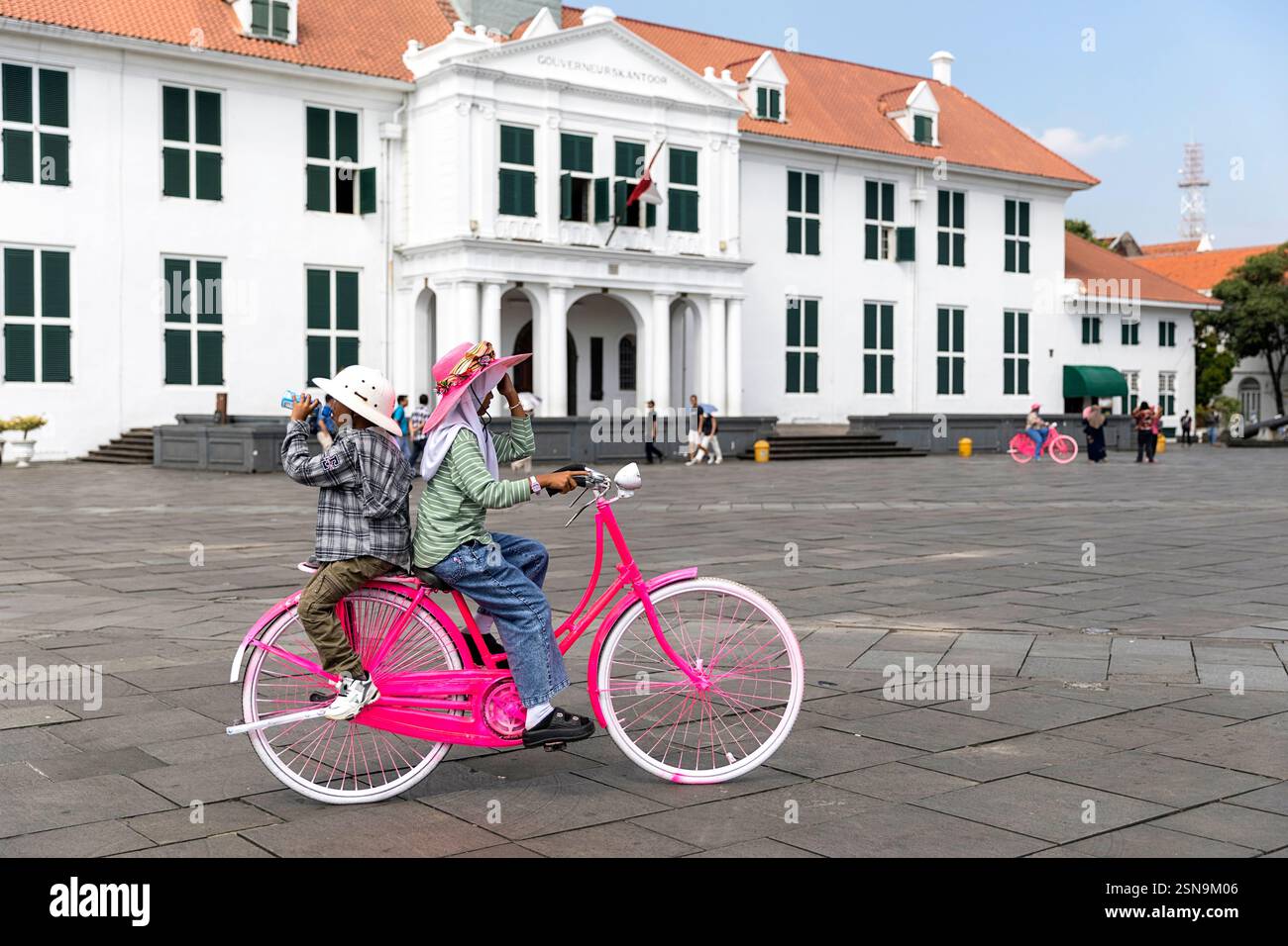 Local tourist kids on a bicycle having fun n the main square of old ...