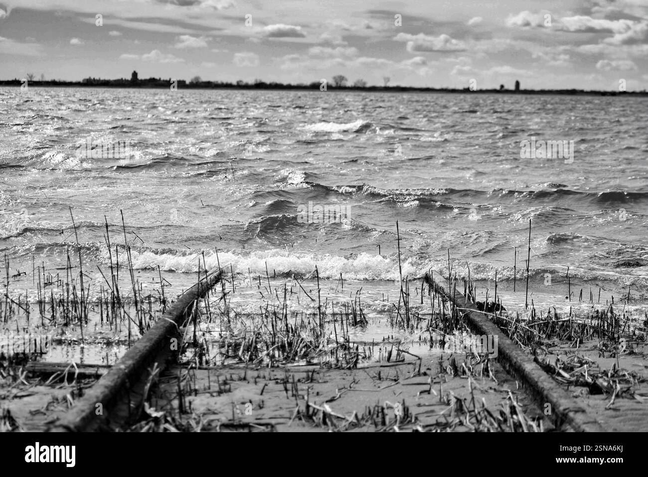Train tracks leading into a body of water. The tracks are partially ...