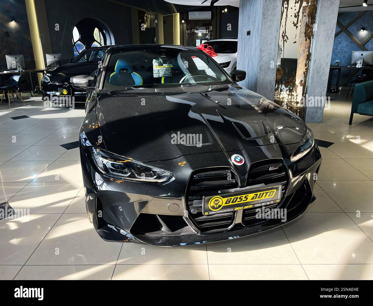 Lviv, Ukraine - February 12, 2025: A sleek black BMW M4 sports car displayed indoors in a ...