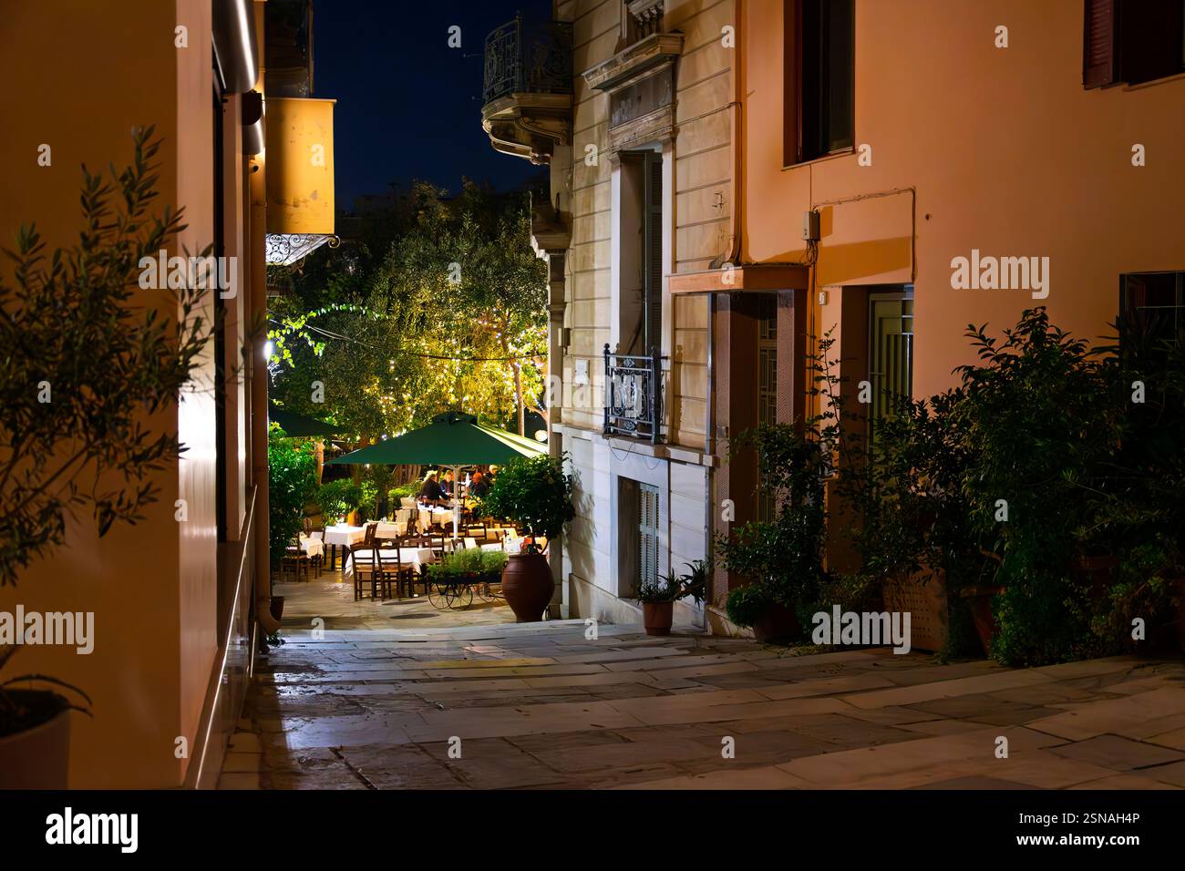 A sidewalk cafe and restaurant on a colorful alley at night in the ...