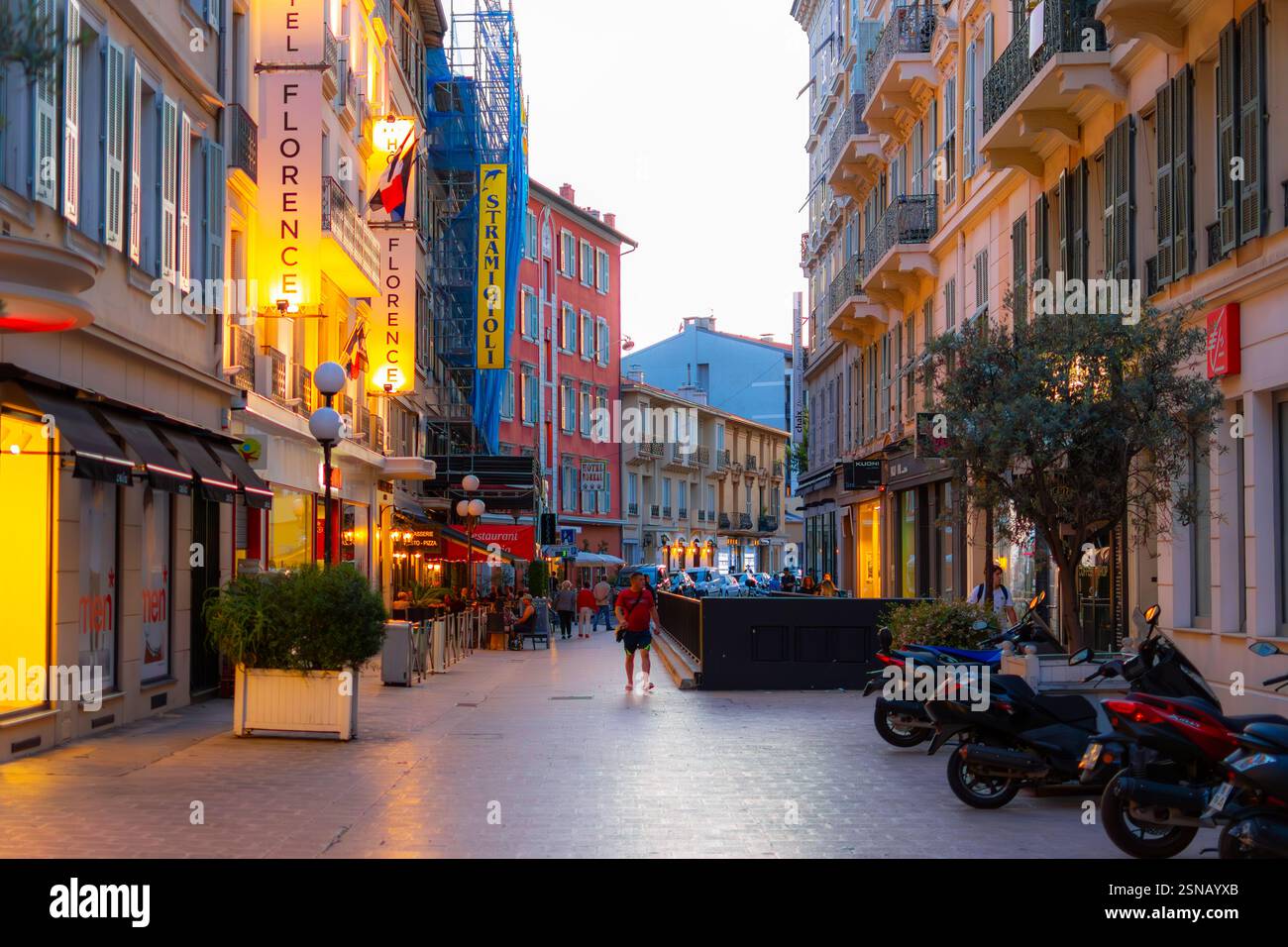 A narrow pedestrian street of colorfully illuminated sidewalk cafes in ...