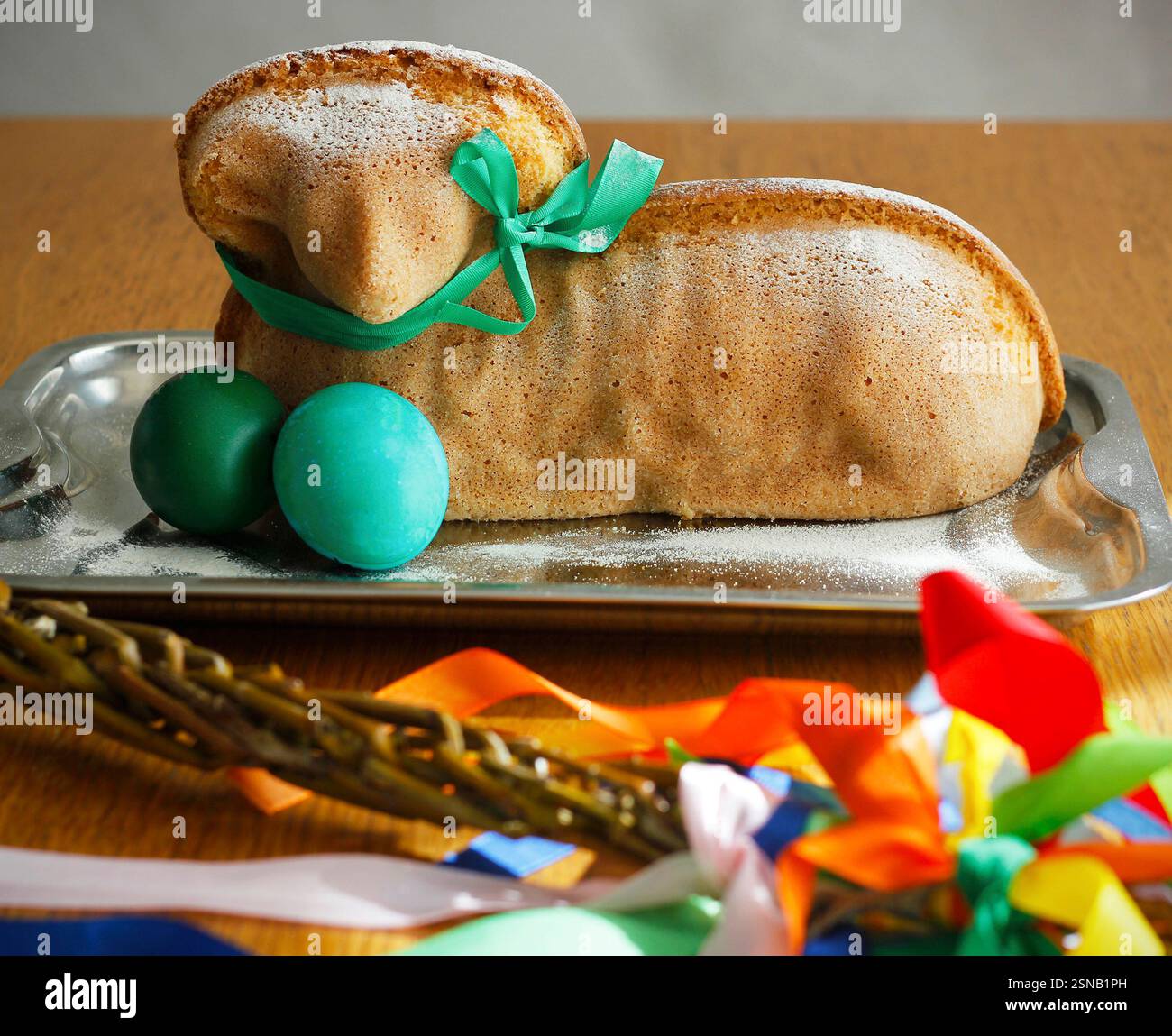 Easter lamb cake with a green ribbon around its neck and painted eggs ...