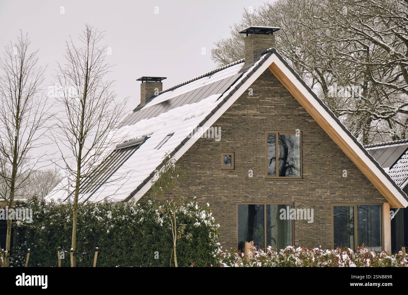 A contemporary Dutch house with solar panels on a snow-covered roof ...
