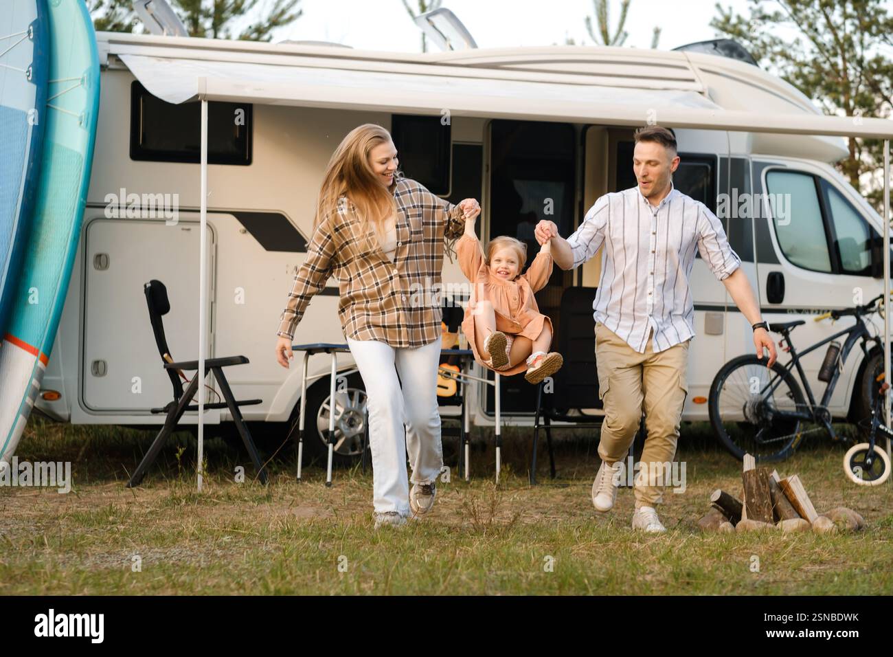 A family enjoys playful moments outdoors as parents swing their child ...