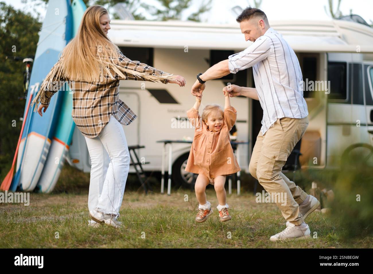 Family enjoys a playful moment, swinging their smiling daughter in the ...