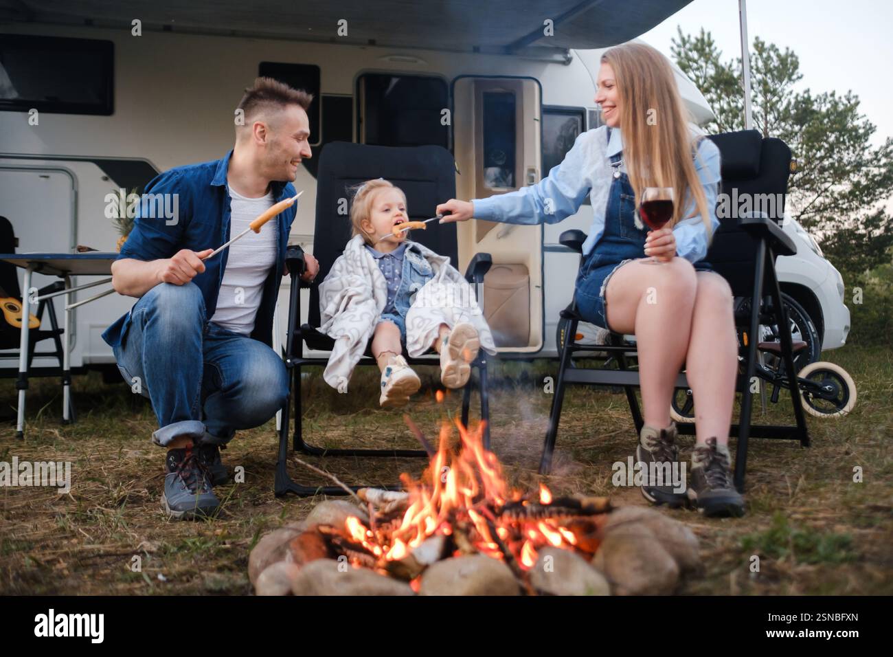 A family enjoys a delightful evening by a campfire. They gather ...