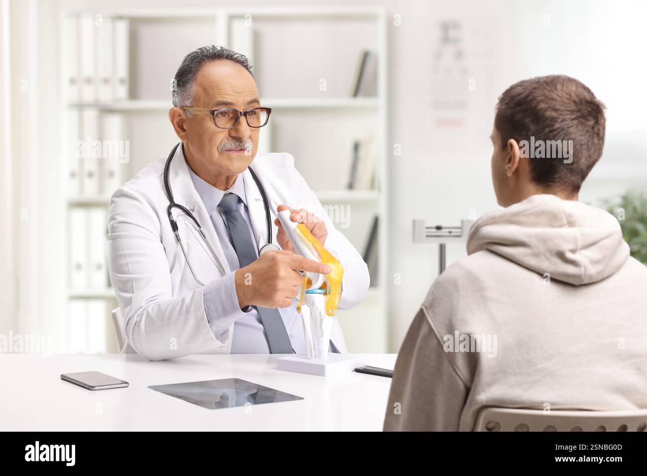 Male doctor explaining a knee joint to a male patient at the office ...