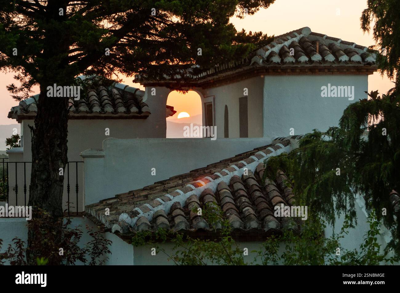 Setting sun seen through the archway of a traditonal Spanish home with ...