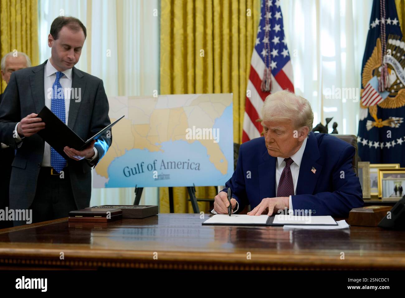 President Donald Trump signs an executive order as White House staff ...
