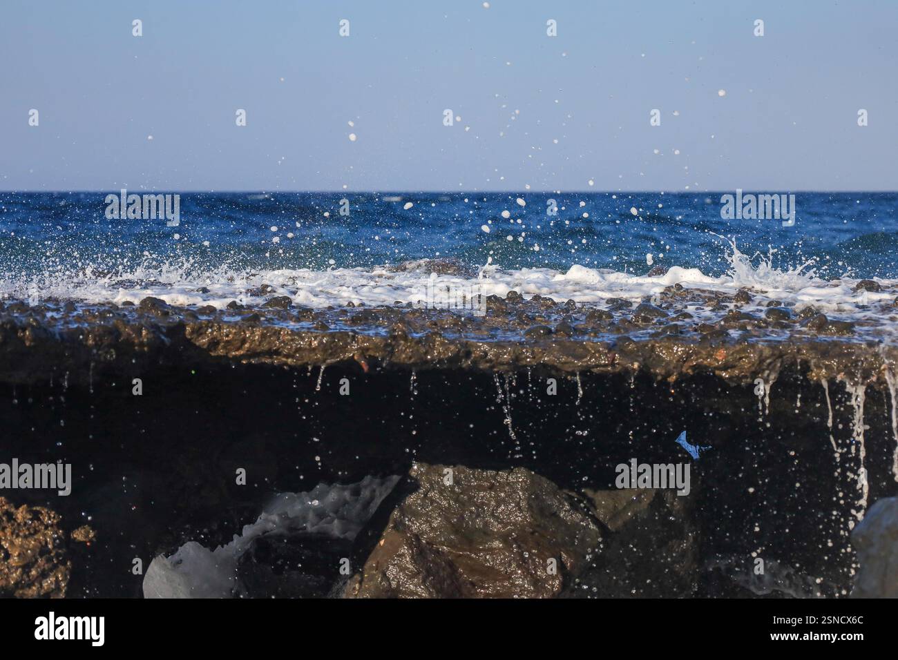 close-up of ocean waves forcefully hitting a rocky seawall, creating ...