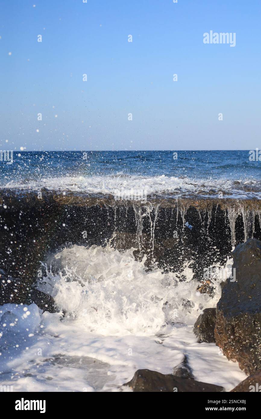 close-up of ocean waves forcefully hitting a rocky seawall, creating ...