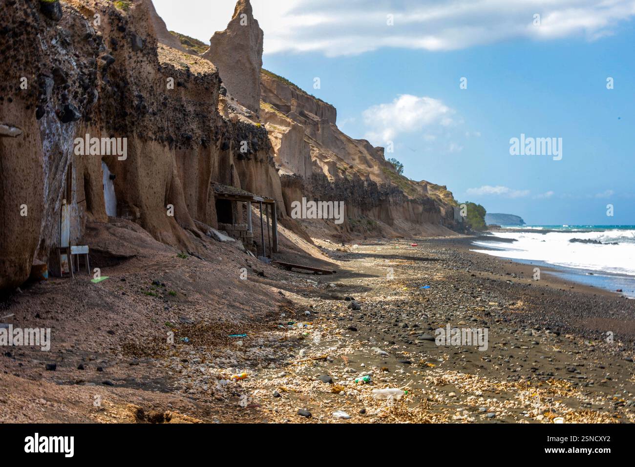 A rugged coastal landscape featuring towering, eroded cliffs with dark ...