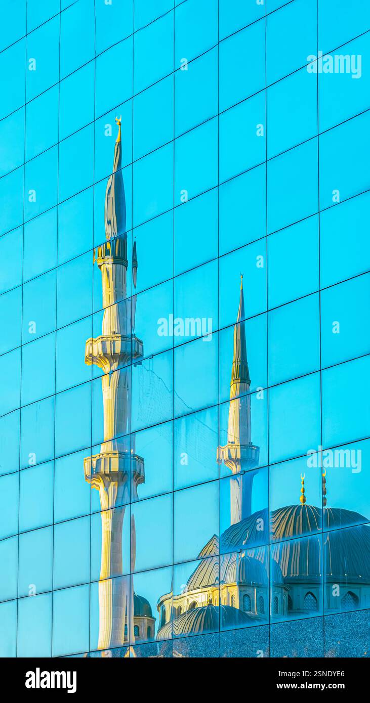 Reflection of an Ottoman mosque with tall minarets in blue glass ...