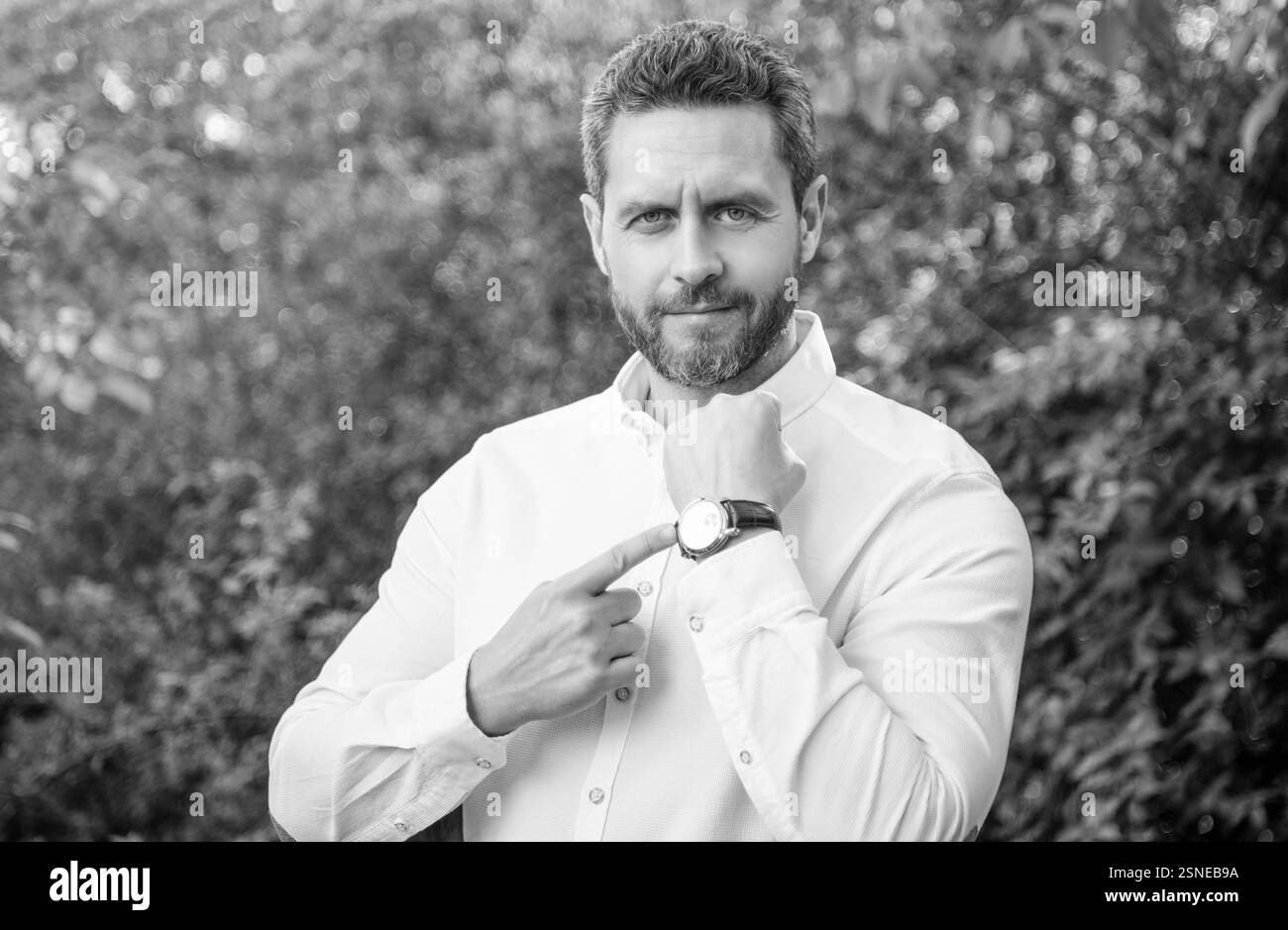 Professional guy pointing finger at wristwatch natural background ...