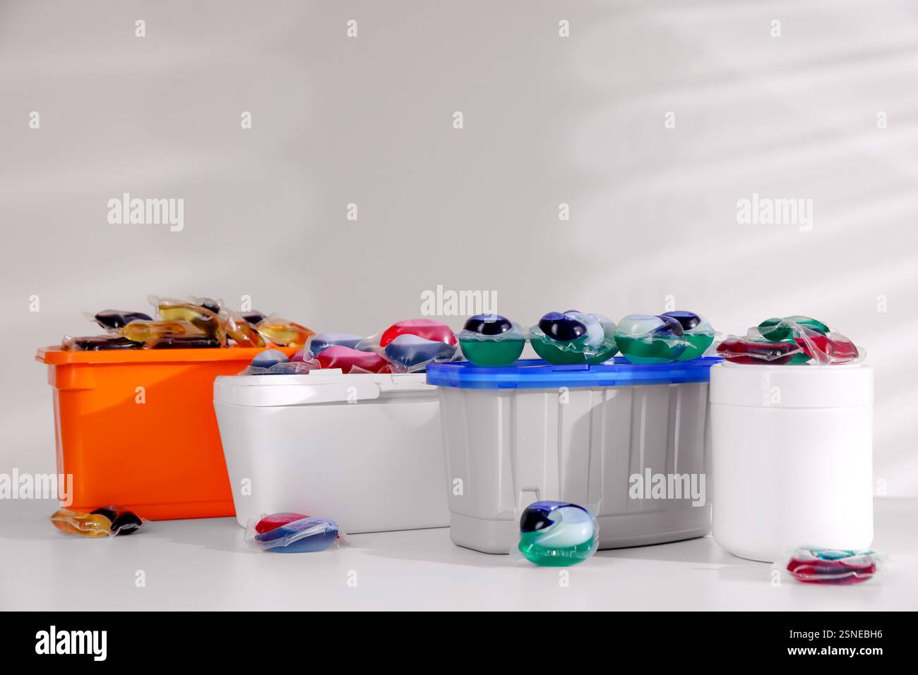 Containers with different laundry detergent capsules on white ...