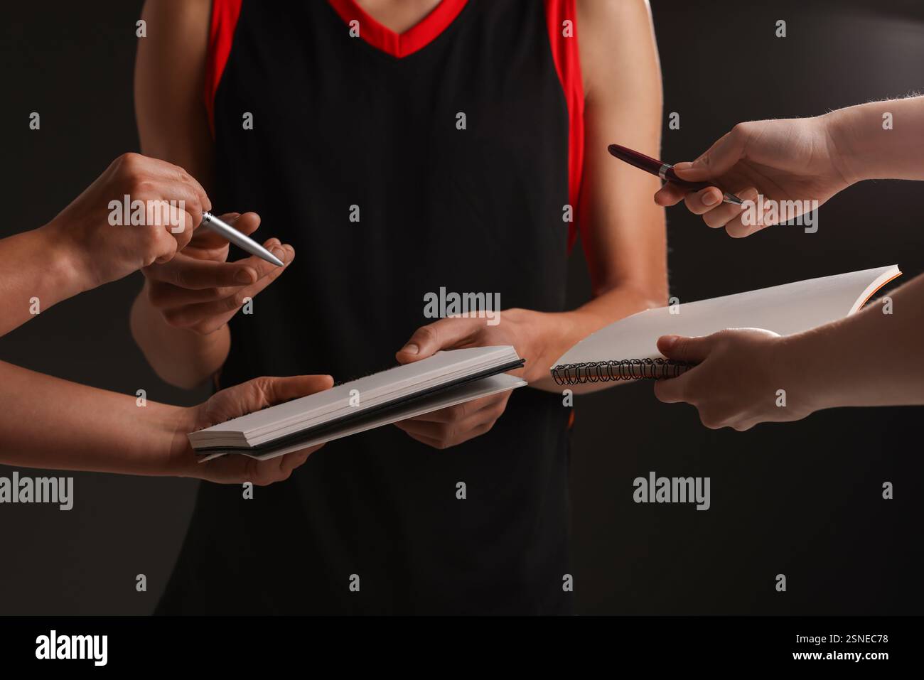 Sportsman signing autograph in notebooks on black background, closeup ...