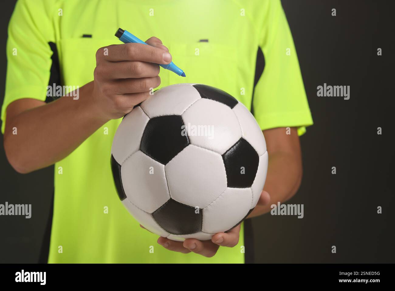 Professional player signing autograph on ball against black background ...