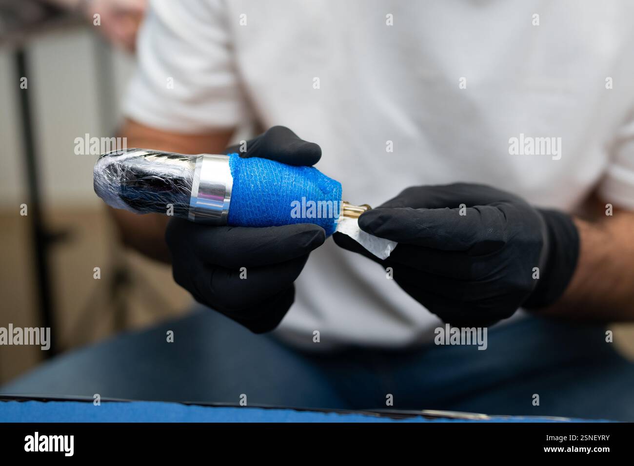 Tattoo artist wearing black gloves carefully cleaning and preparing a ...