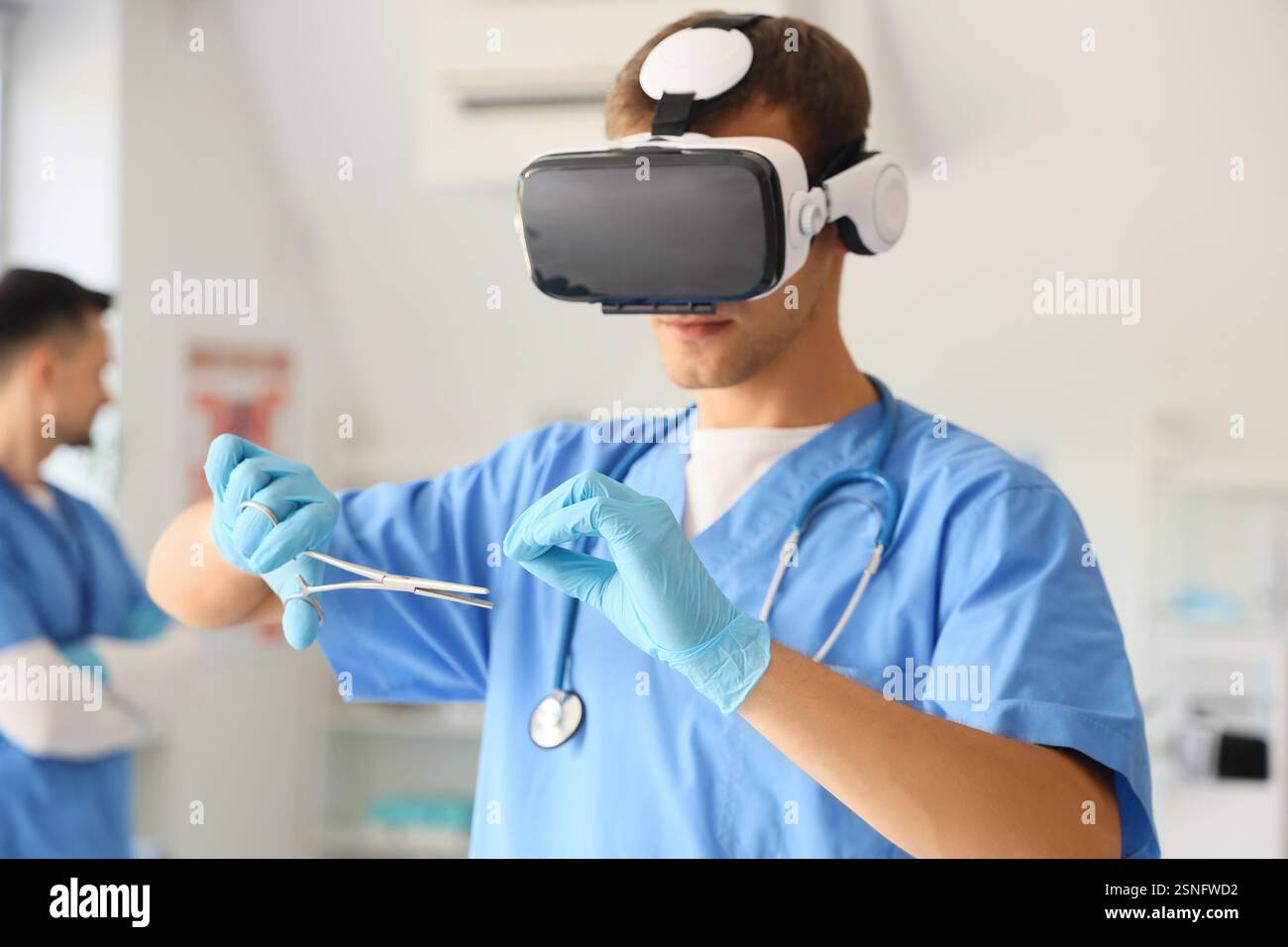 Male doctor with medical scissors using VR glasses in clinic Stock ...