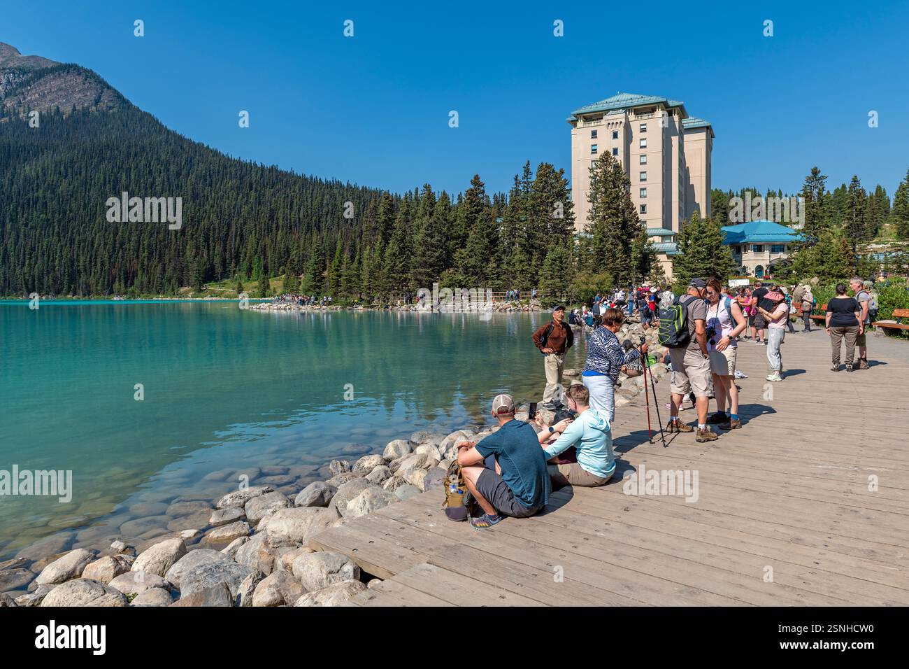 People hiking along Lake Louise with hotel in background, Banff ...