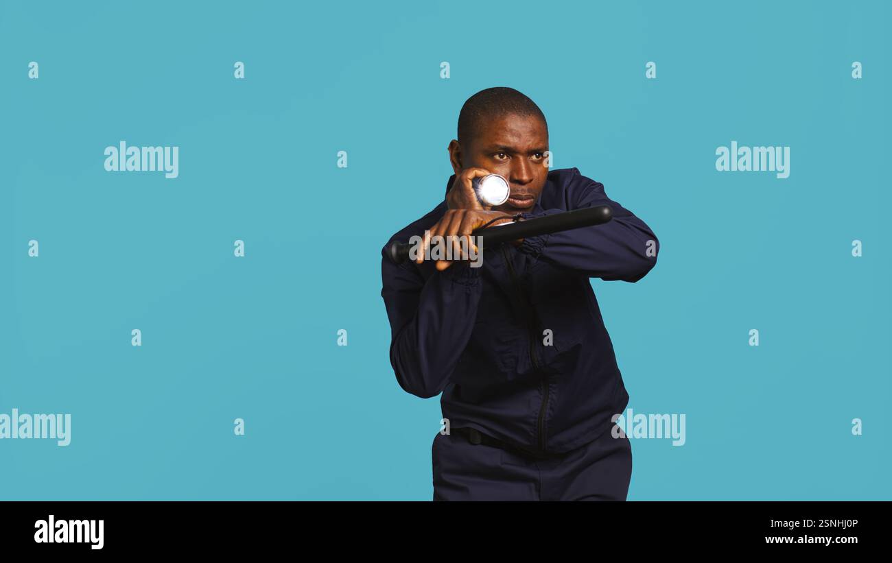 Security guard turning on flashlight and preparing baton to detect and ...