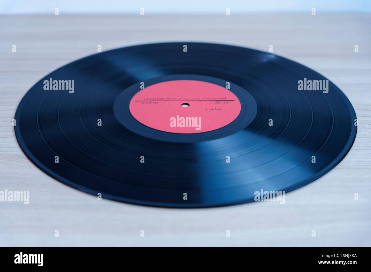 Classic black vinyl record with a red label lying on a wooden ...