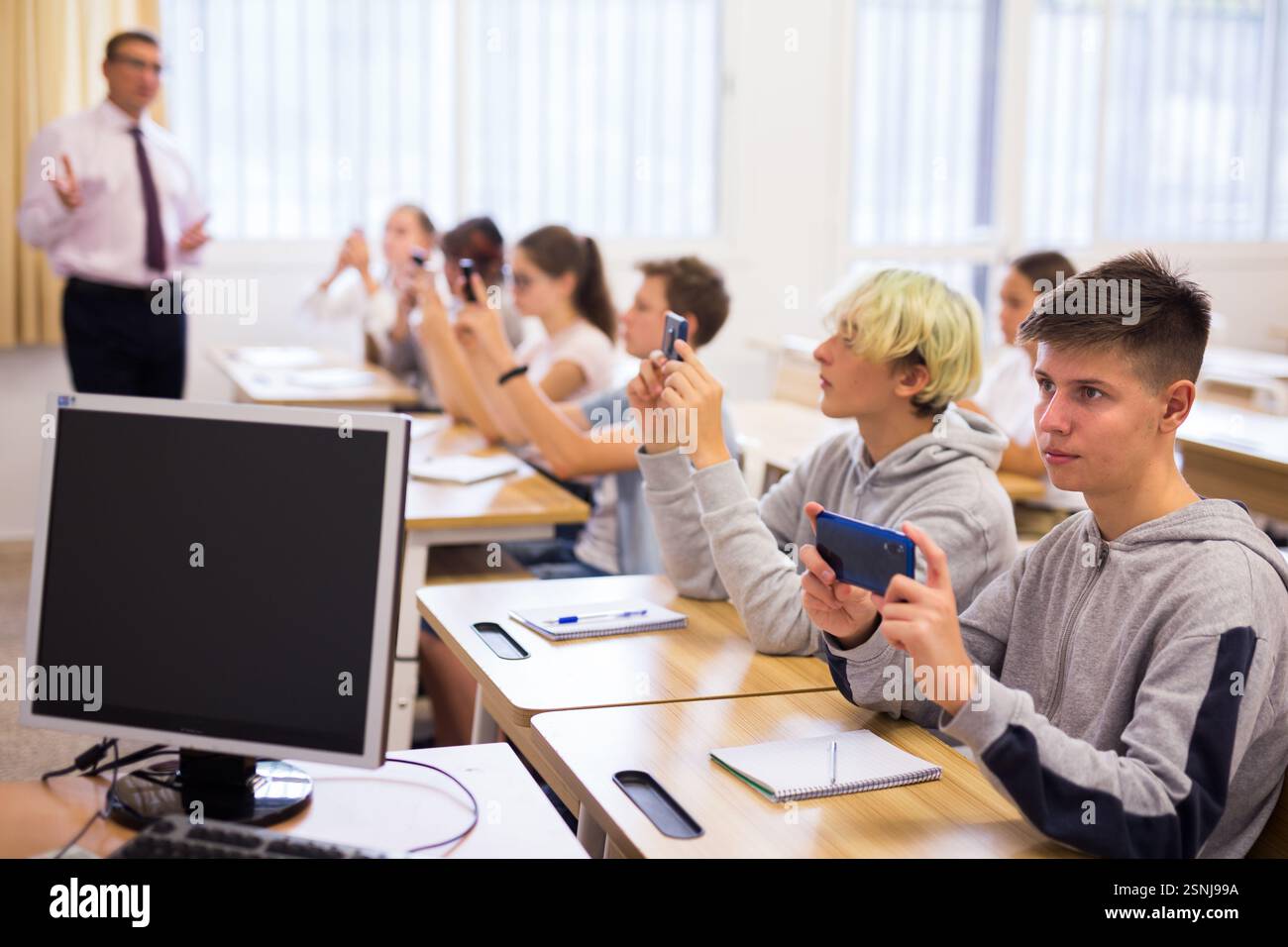 Teenage students using smartphones during lesson Stock Photo - Alamy