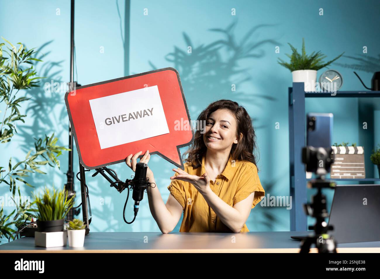 Cheerful vlogger advertising giveaway for viewers with cardboard sign ...
