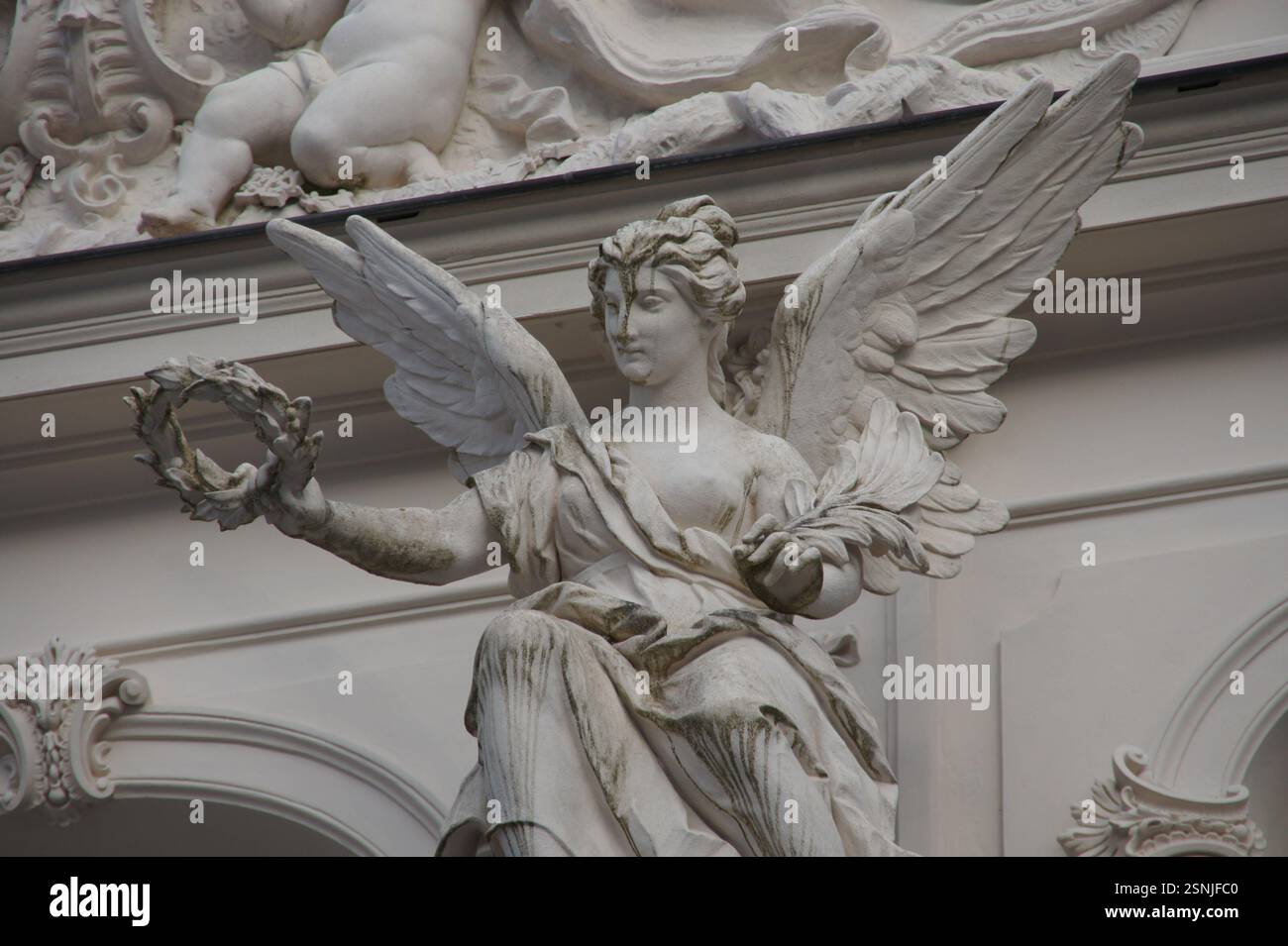 Atop a building in Germany, Munich, stands a statue of an angel holding ...