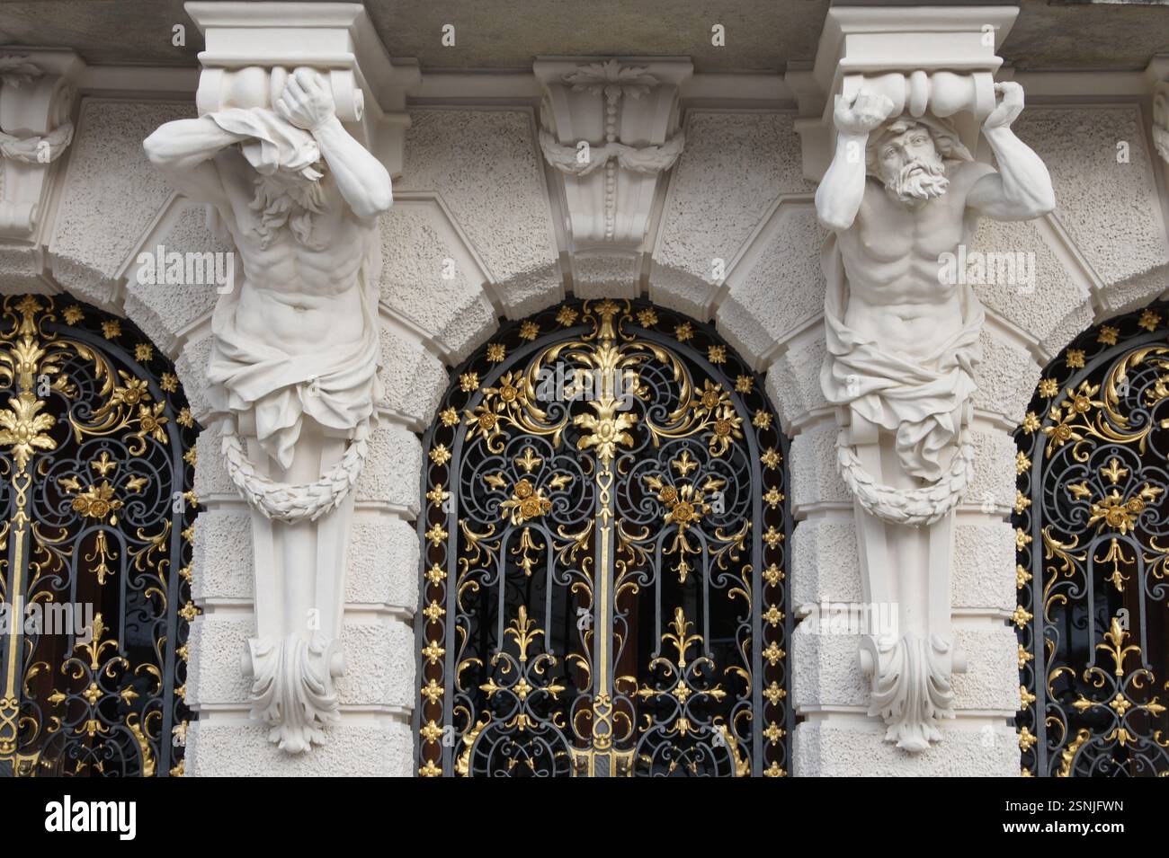 A large, classical statue of a man stands on the side of a building in ...