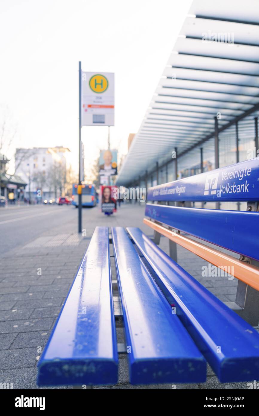 Blue bench at a modern bus stop with glass roof in an urban environment ...