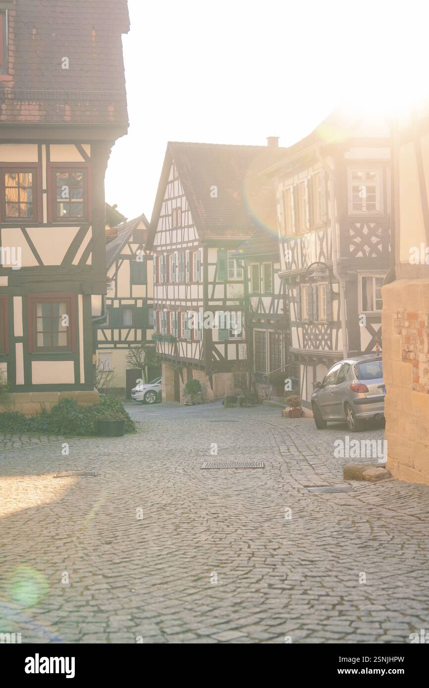 Warm rays of sunlight illuminate a cobbled area with charming half ...