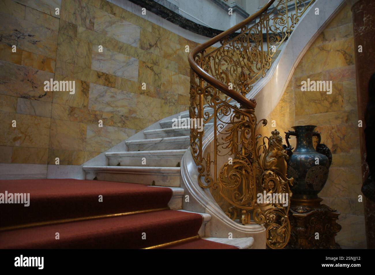 Germany, Munich. A grand staircase with a gold railing winds upwards ...