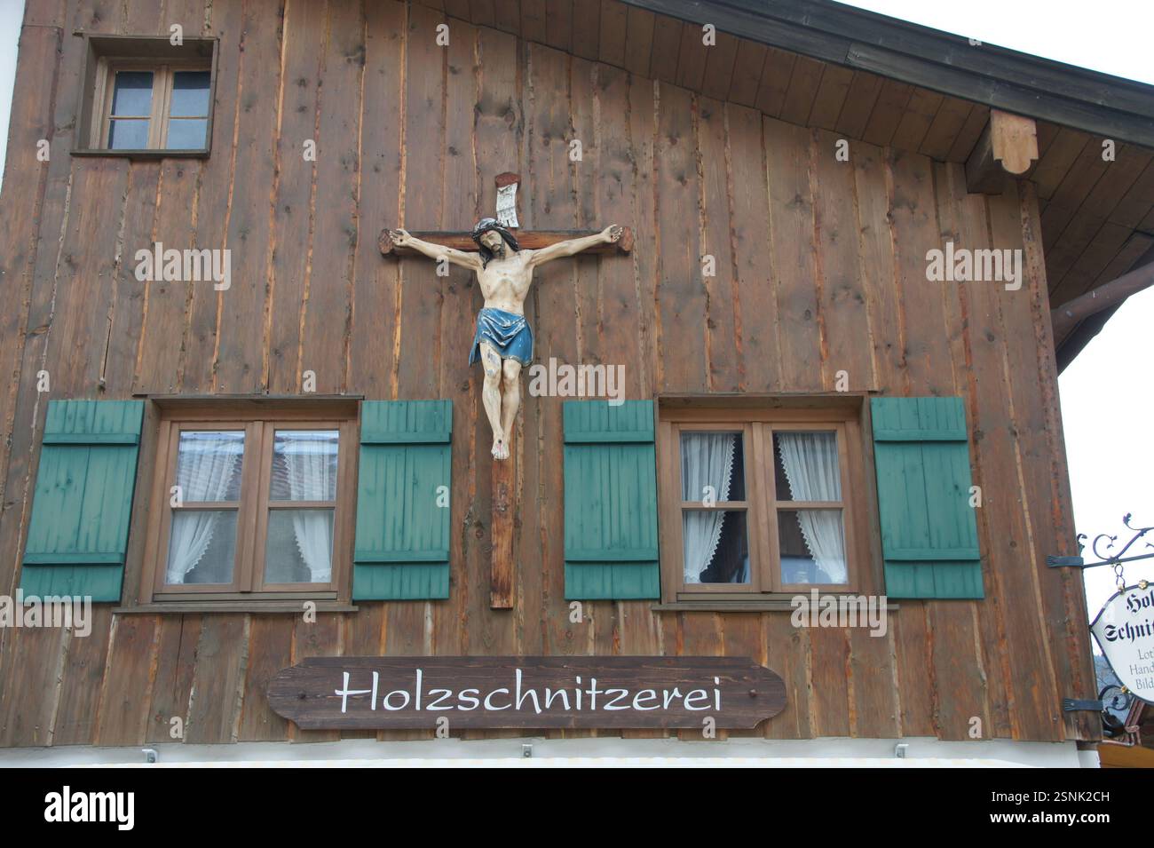 A wooden crucifix with a statue of Jesus Christ adorns the facade of a ...