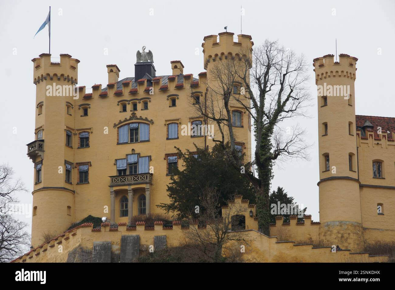 The photo shows a yellow castle with two towers on top of a hill in ...