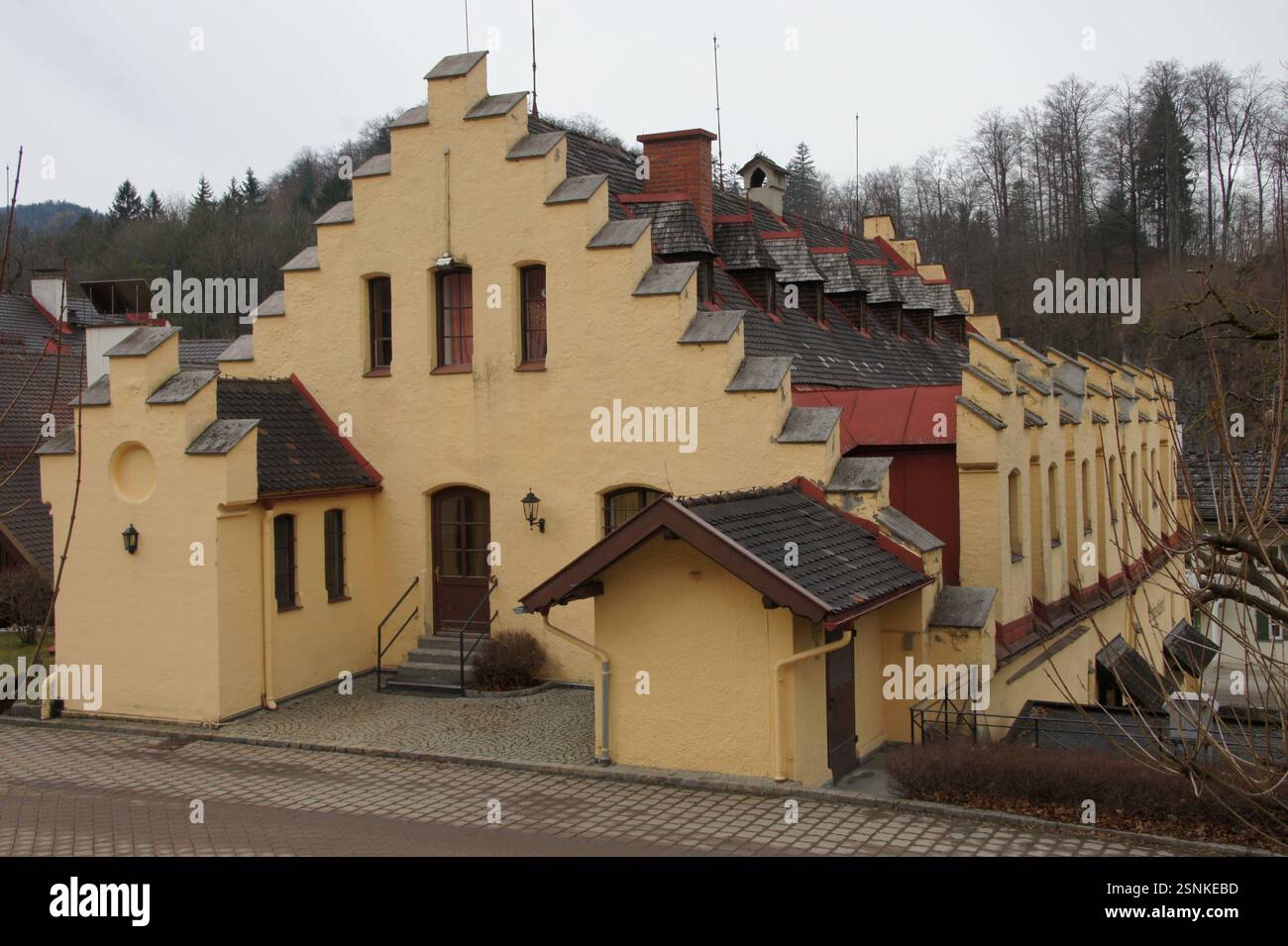 A yellow castle with a red roof sits atop a hill in Germany, Munich. A ...