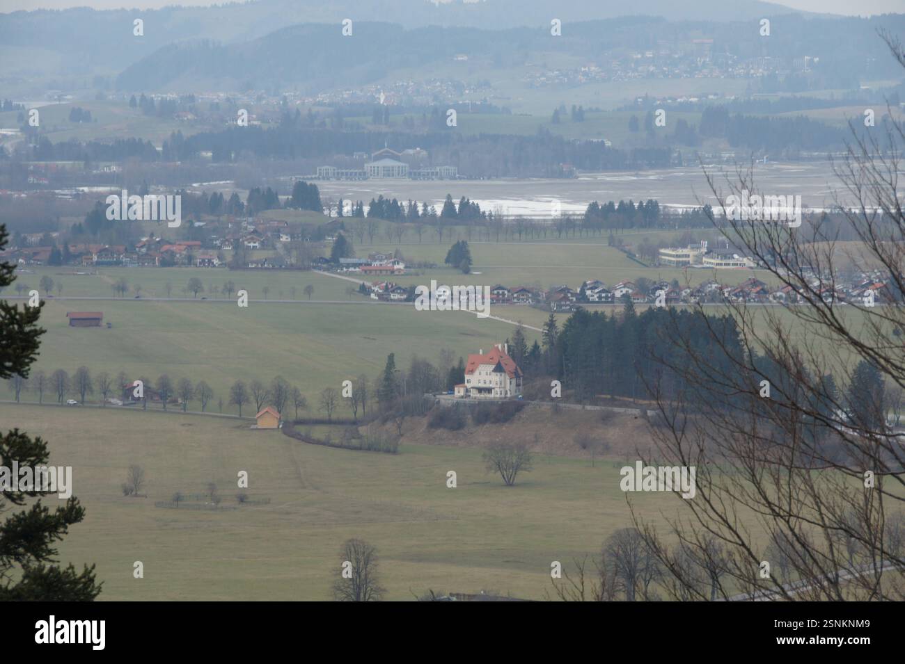 A white house with a red roof sits atop a hill in Germany, Munich. Lush ...