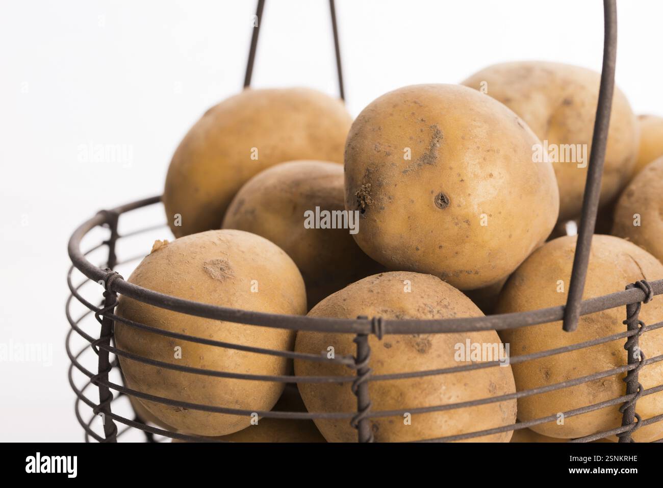 Uncooked potatoes in wire basket Stock Photo - Alamy