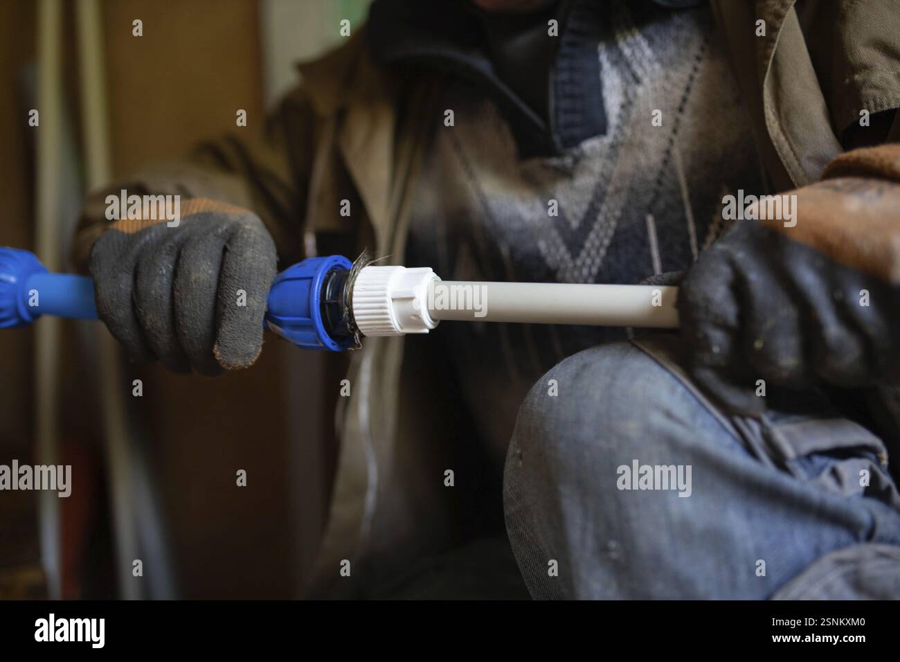 Close-up of gloved hands adjusting a pipe fitting Stock Photo - Alamy